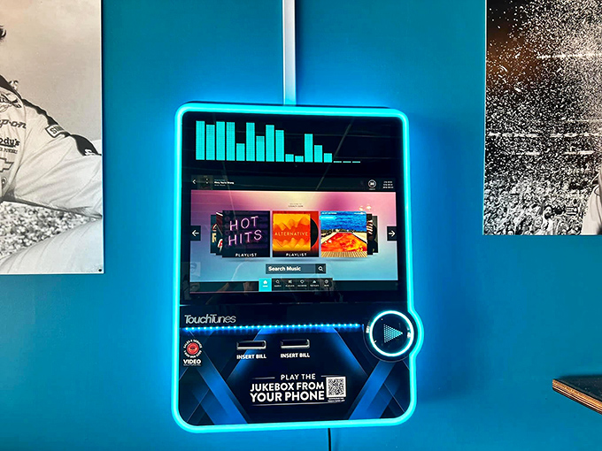 The modern jukebox glows with neon promise—pick your soundtrack and let the music enhance flavors that already sing on their own.