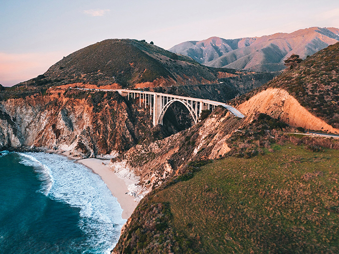 The iconic Bixby Bridge stands as a testament to human ingenuity amid nature's raw power, just a short drive from Pfeiffer's purple shores.
