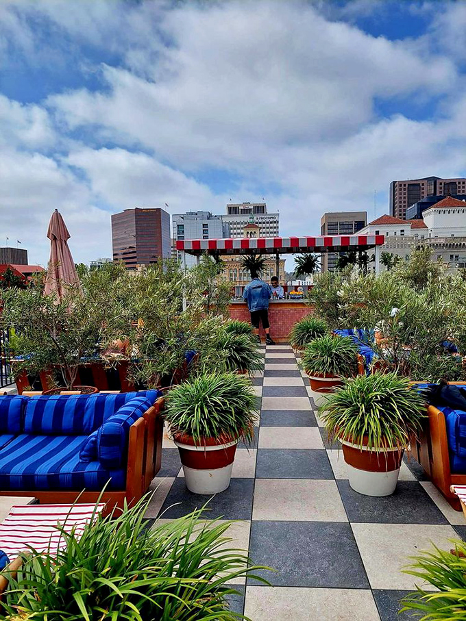 The outdoor patio offers an urban oasis with its checkerboard floors and lush greenery. Blue cushions pop against terracotta planters&mdash;California sunshine meets French sensibility.