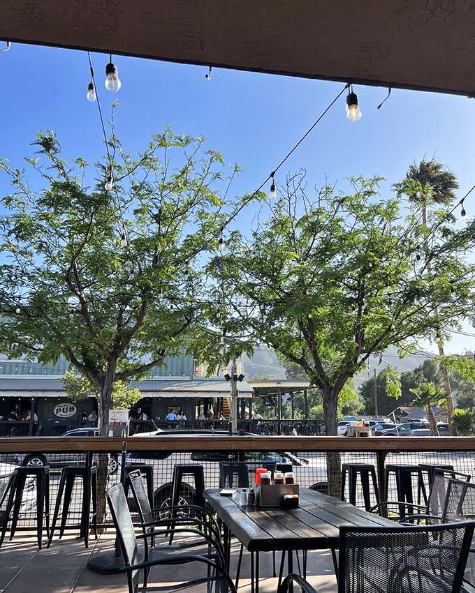 The outdoor patio captures that magical California vibe where string lights, shade trees, and the promise of good food create the perfect escape.