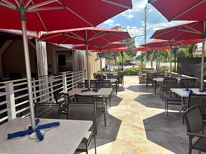 The outdoor patio with its signature red umbrellas offers al fresco dining where gentle breezes carry conversations and the scent of fresh seafood.