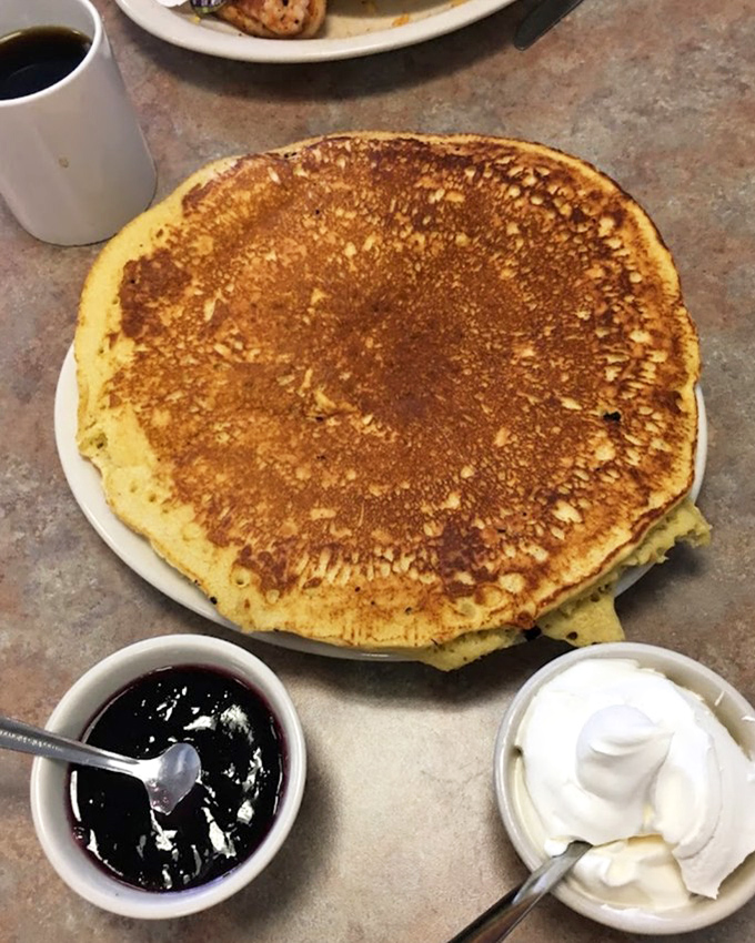 A pancake so perfectly golden it belongs in the breakfast hall of fame, with grape jelly and whipped cream standing by for supporting roles.