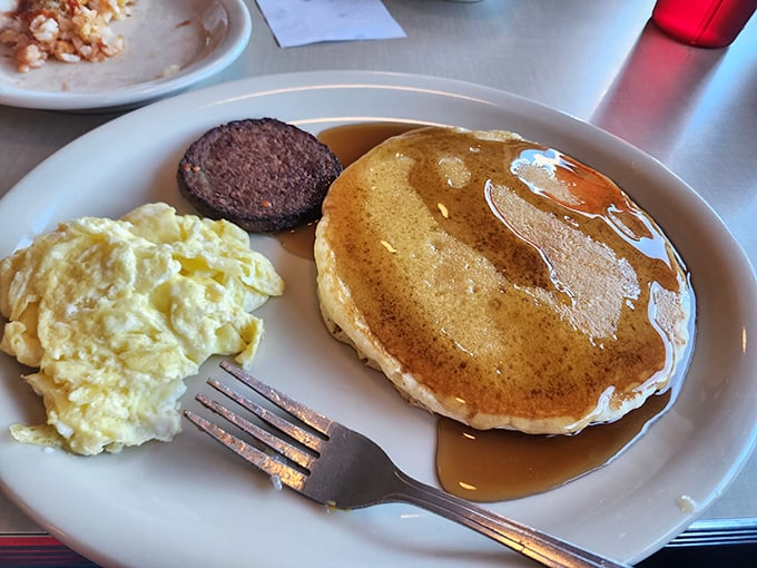 Pancakes golden as Alabama sunshine, eggs scrambled to perfection, and sausage that makes plant-based alternatives weep with inadequacy.