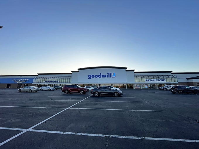As dusk approaches, the Goodwill glows with possibility. Each car in this lot represents someone's thrifting adventure in progress.