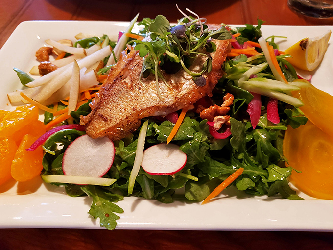A vibrant salad topped with perfectly seared fish proves that sometimes the lighter options at a seafood restaurant deserve the spotlight too.