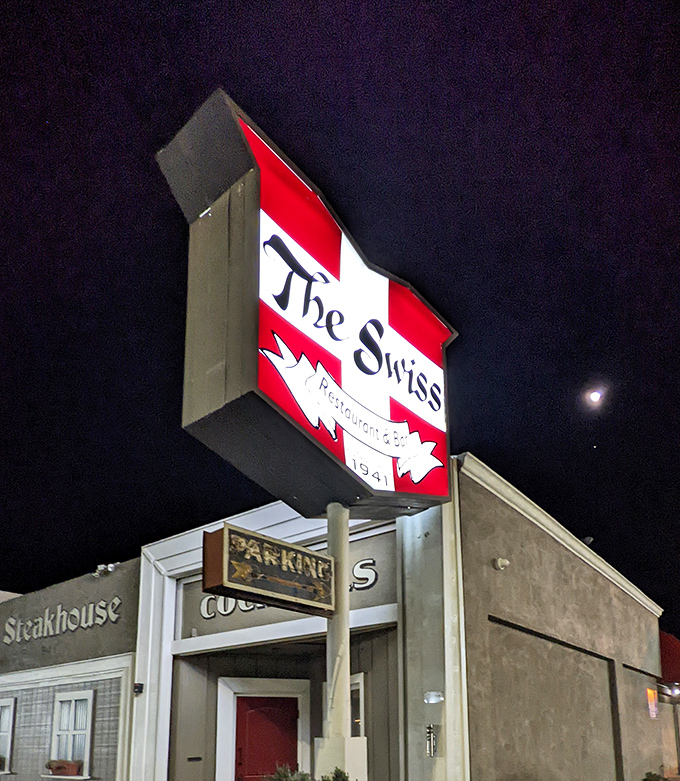 The Swiss Restaurant sign glowing against the night sky&mdash;a beacon for hungry travelers and locals alike.