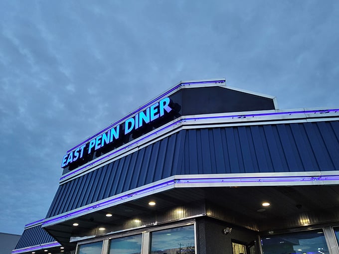 As evening approaches, the East Penn Diner sign glows with neon promise against the twilight sky&mdash;a blue-lit beacon for hungry travelers.