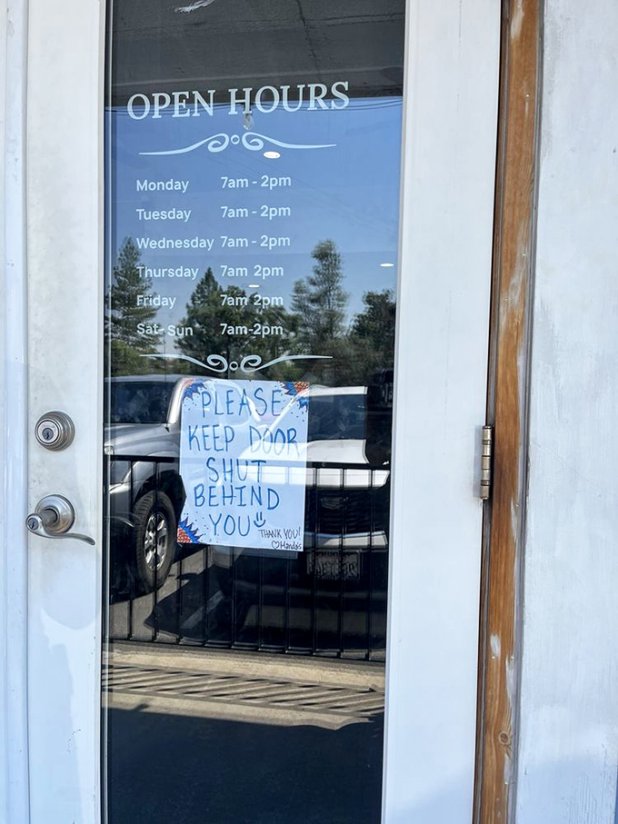 Hours posted with a handwritten reminder to keep the door shut&mdash;small-town charm that's worth setting your alarm for.