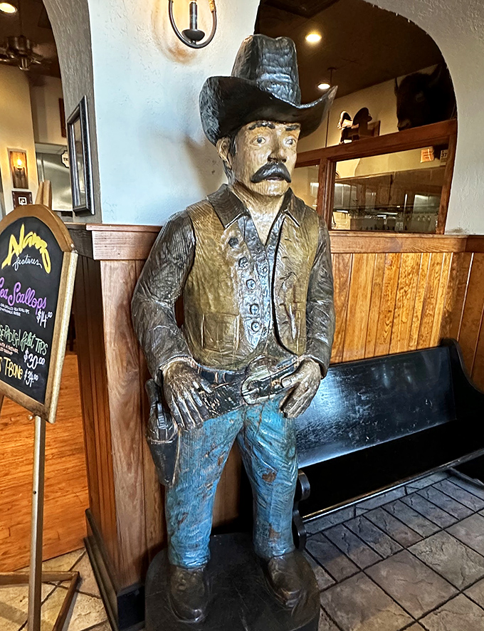 This wooden cowboy stands guard, silently judging those who order their steaks well-done. His disapproving eyes follow you to your table.