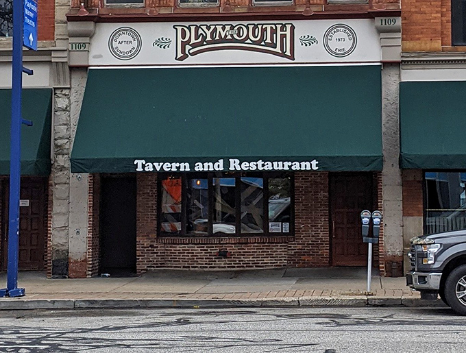 The simple green awning and brick storefront blend seamlessly into downtown Erie's historic streetscape below.