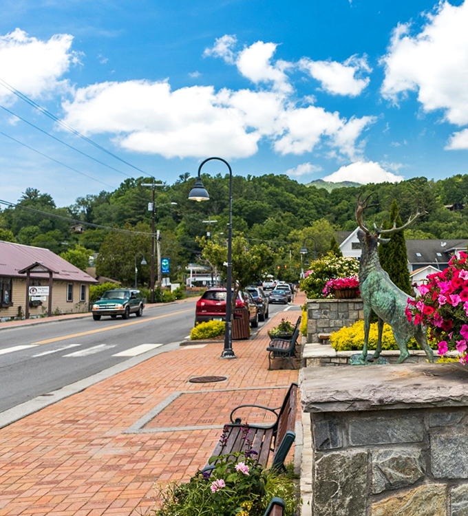 Banner Elk's iconic elk statue stands sentinel over brick sidewalks and blooming flowers, a bronze guardian of small-town charm.