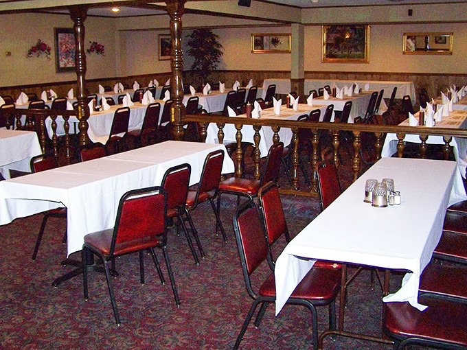 White tablecloths and red chairs create an elegant setting where serious barbecue meets refined dining room comfort.