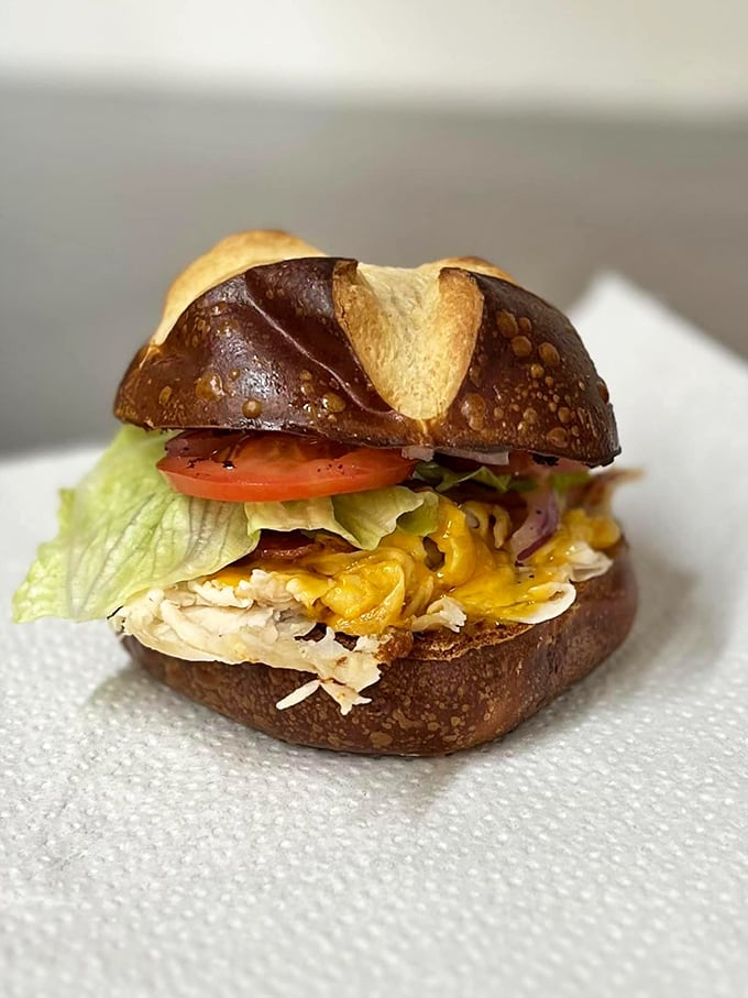 This isn't just a sandwich; it's a masterpiece on a pretzel bun where every ingredient plays its part in perfect harmony.