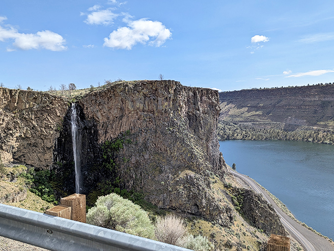 The dramatic waterfall cascades down ancient rock faces, adding a theatrical element to the already spectacular canyon lake scenery below.