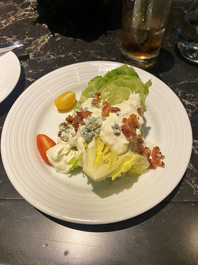 The wedge salad arrives like iceberg architecture, blue cheese avalanching down its sides with bacon confetti celebrating on top.