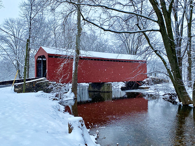 Winter transforms the scene into a holiday card come to life. The red bridge against snow-covered banks creates a magical Maryland moment.