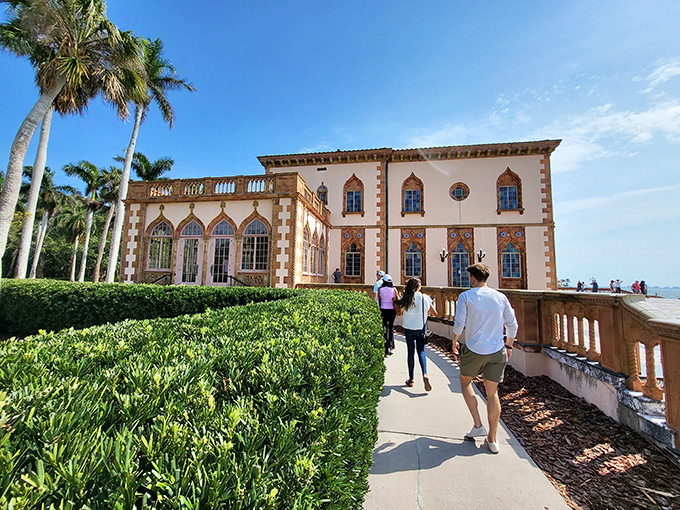 Visitors stroll along Ca' d'Zan's bayfront path, experiencing the same views that once enchanted America's elite during the Roaring Twenties.