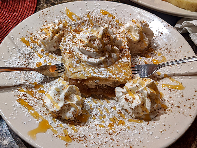 Apple strudel crowned with whipped cream and caramel drizzle&mdash;the kind of dessert that makes you consider ordering a second before finishing the first.
