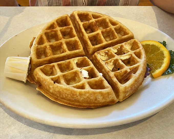 This golden waffle with its perfect grid of syrup-catching squares stands ready for butter's melting embrace&mdash;breakfast architecture at its finest.
