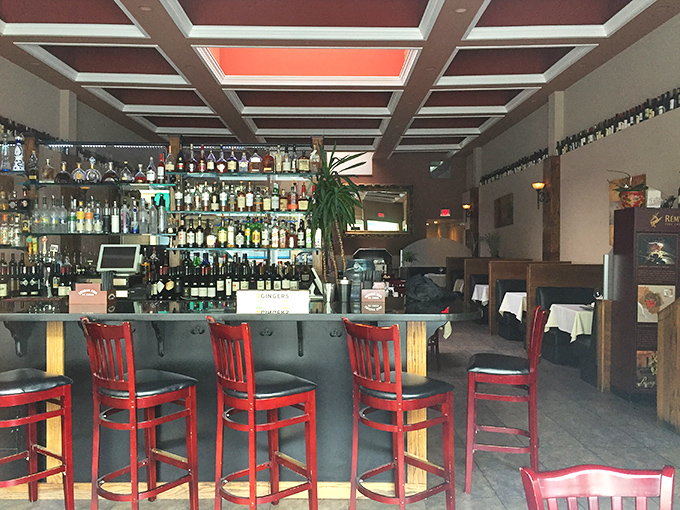 The well-stocked bar promises liquid courage before your meat adventure. Those red chairs practically whisper, "Stay for one more."