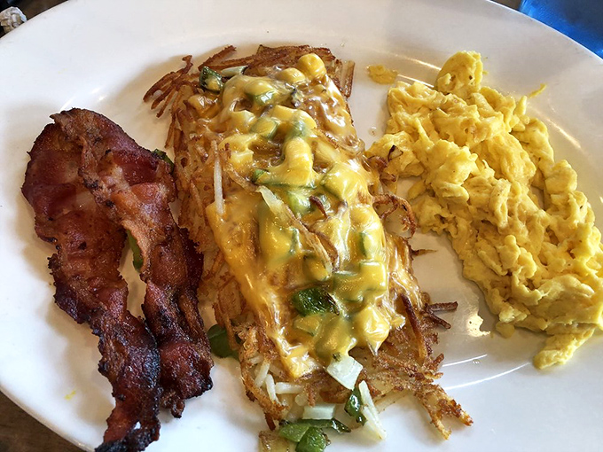 The perfect breakfast trifecta: crispy bacon, golden hash browns with melty cheese, and eggs scrambled to textbook perfection.