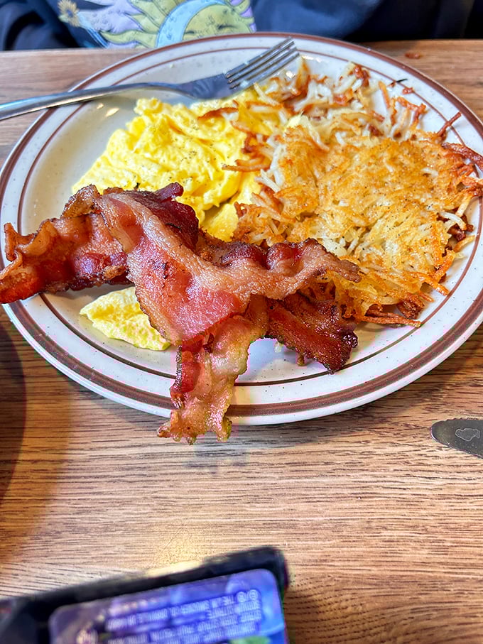 The holy trinity of breakfast: perfectly scrambled eggs, hash browns with the ideal crisp-to-soft ratio, and bacon that demands respect.