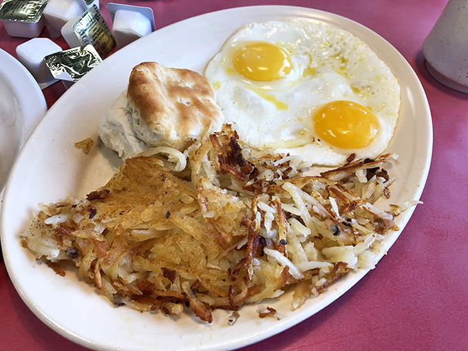 The holy trinity of breakfast: perfectly crispy hash browns, sunny-side-up eggs, and a biscuit that would make any Southern grandmother nod in approval.
