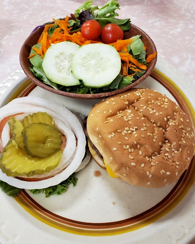 The classic burger setup &ndash; sesame seed bun, melted cheese, fresh veggies, and pickles on the side for those who understand that condiment control is personal.