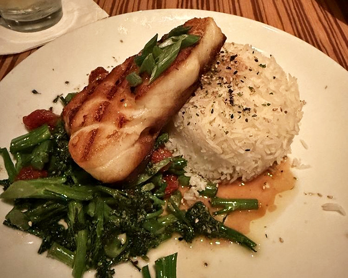 Chilean sea bass perched atop vibrant greens with a side of rice that's anything but an afterthought. The kind of plate that makes you pause to take a photo first.