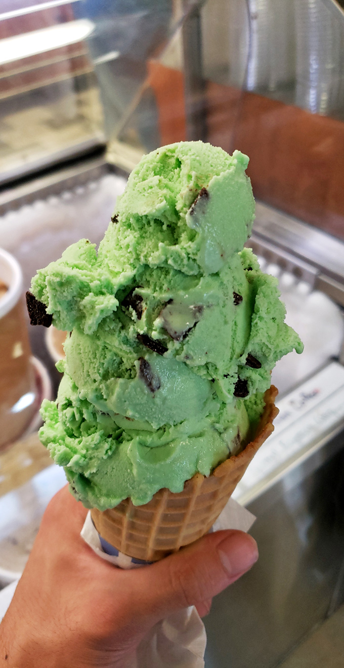 Mint chocolate chip stacked impossibly high on a waffle cone&mdash;not just dessert, but a structural marvel that demands to be photographed before devoured.