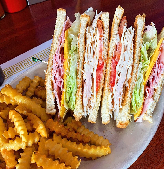 The club sandwich&mdash;architectural marvel of turkey, bacon, and vegetables between perfectly toasted bread. Those crinkle fries aren't just along for the ride&mdash;they're essential co-stars.