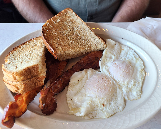 The breakfast plate that launched a thousand road trips—perfectly cooked eggs, crispy bacon, and toast that makes you nostalgic for simpler times.