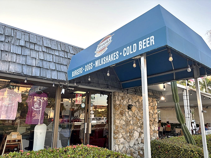 The blue awning proudly announces "BURGERS &bull; DOGS &bull; MILKSHAKES &bull; COLD BEER"&mdash;four horsemen of the appetite apocalypse.