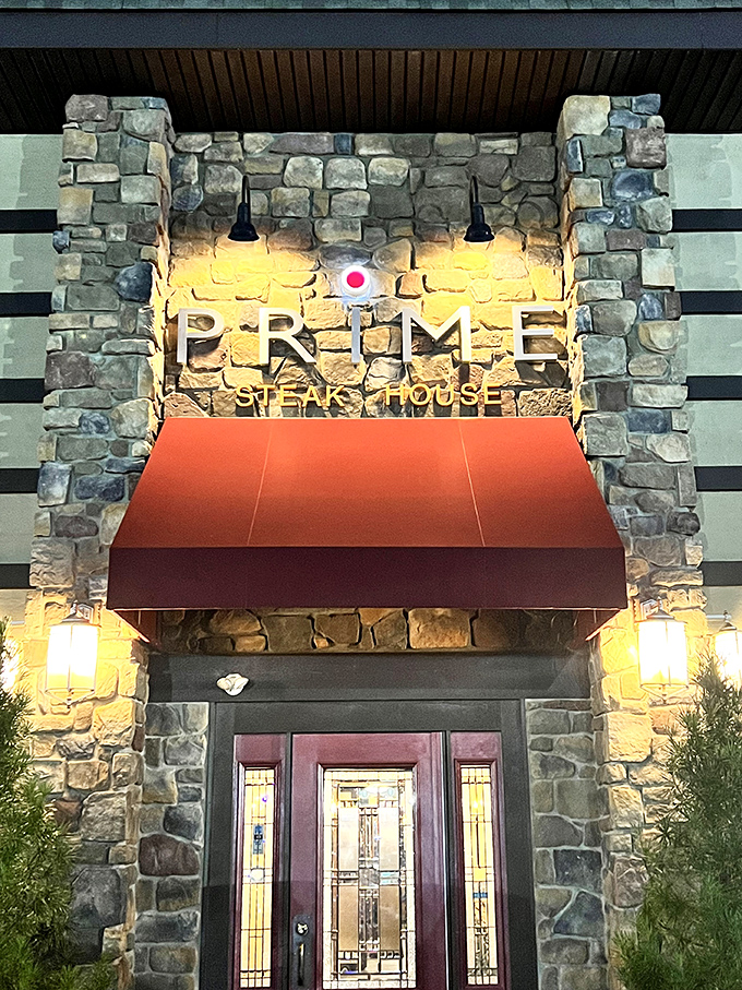 Evening transforms Prime's entrance into a beacon of gastronomic promise, the illuminated stonework practically whispering "steak night."
