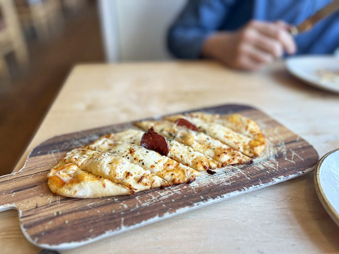 This flatbread isn't just food&mdash;it's edible architecture. Perfectly charred, topped with cheese and what appears to be prosciutto, it's hand-held happiness.