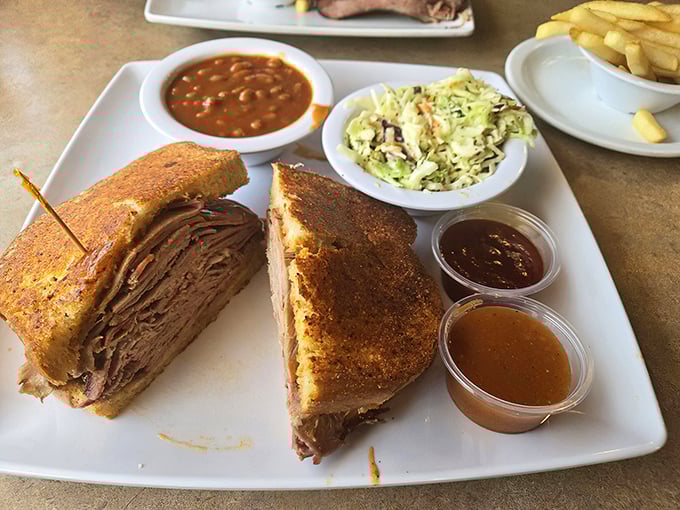 This isn't just a sandwich&mdash;it's architecture. Layers of perfectly smoked meat with coleslaw, beans, and sauce cups standing by for customized flavor adventures.