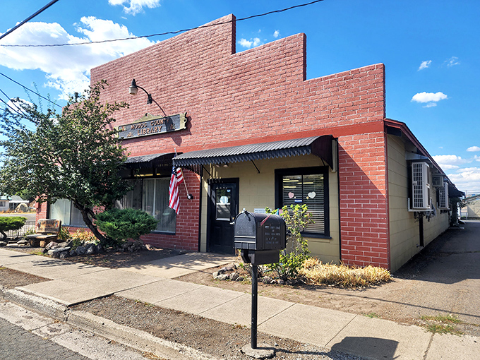 This brick building with American flag represents small-town business resilience, where personal service hasn't been replaced by automated phone systems from customer service hell.