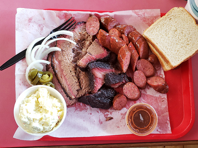 The carnivore's dream platter – where brisket, sausage and ribs coexist in harmony on butcher paper, proving that world peace might start with BBQ.