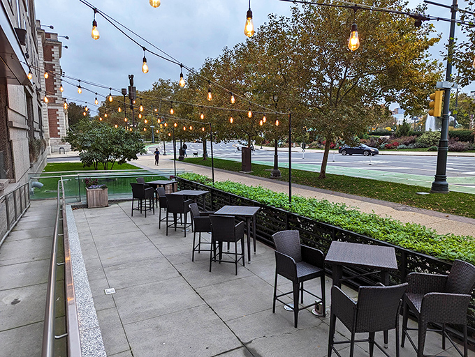 The outdoor seating area offers urban tranquility under string lights, where city energy meets al fresco relaxation in perfect harmony.