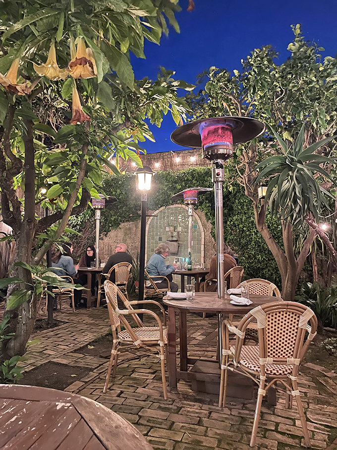 The hidden garden patio feels like stumbling into a secret Mediterranean courtyard—string lights and heat lamps creating dining magic.