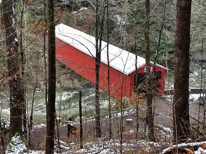 Winter transforms the scene into a holiday card come to life, with snow dusting the bridge's roof and turning Slippery Rock Creek into a landscape of quiet beauty.