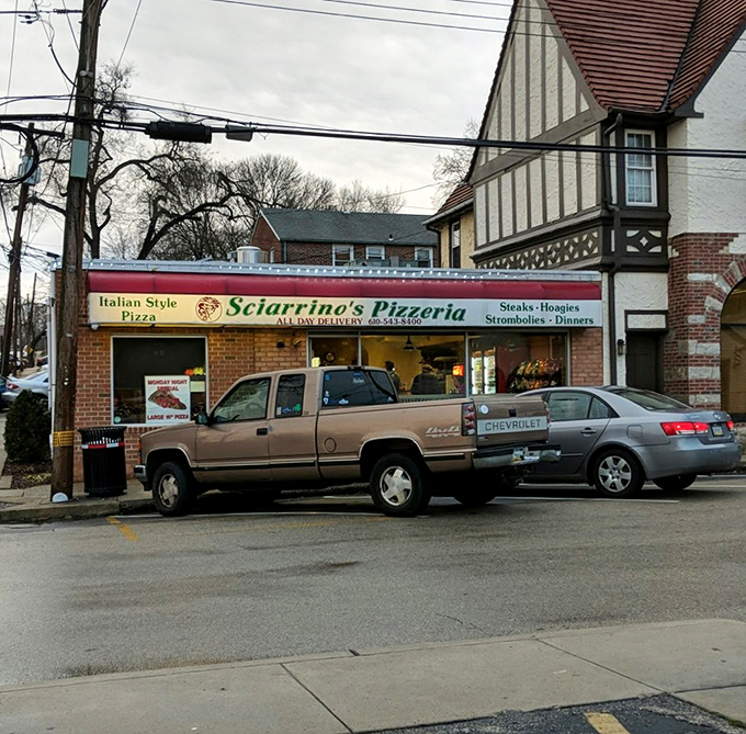 The parking lot view reveals Sciarrino's true place in the community—a modest storefront nestled between residential buildings, serving neighbors for generations.