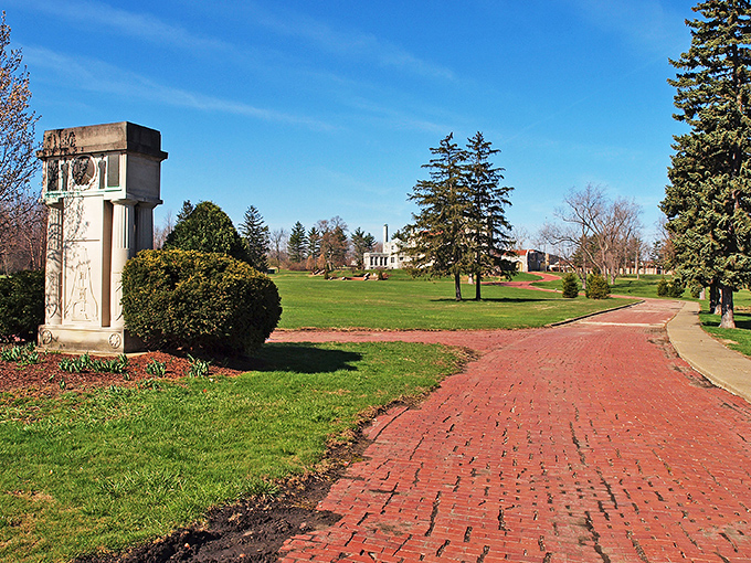 A stone monument stands sentinel along the brick pathway, guiding visitors toward a castle experience that feels delightfully out of place in Ohio.