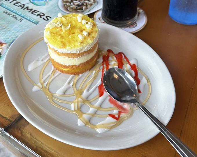 This isn't just dessert, it's architecture – a pineapple cheesecake tower drizzled with enough sauce to make your spoon very, very busy.