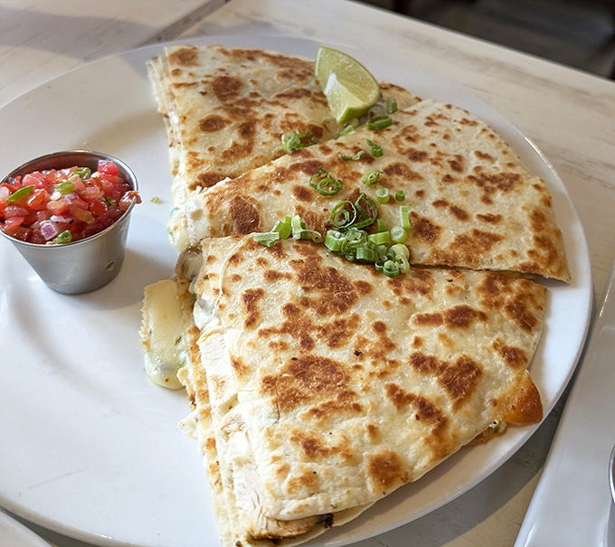 A quesadilla that's achieved the golden-brown perfection we all aspire to in life. That little cup of salsa is about to make a very important contribution.