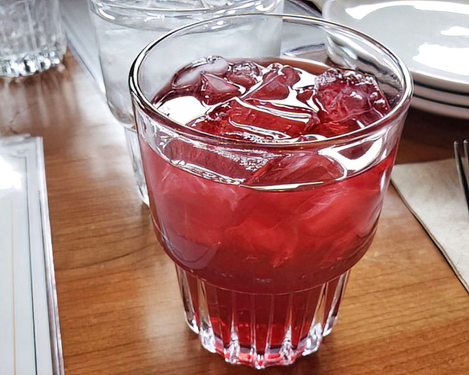 That ruby-red beverage isn't just a drink; it's liquid refreshment art—tangy, sweet, and exactly what you need between bites of pizza perfection.