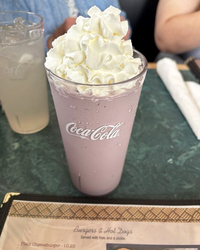 A milkshake thick enough to require serious straw commitment, topped with a cloud of whipped cream that defies gravity.