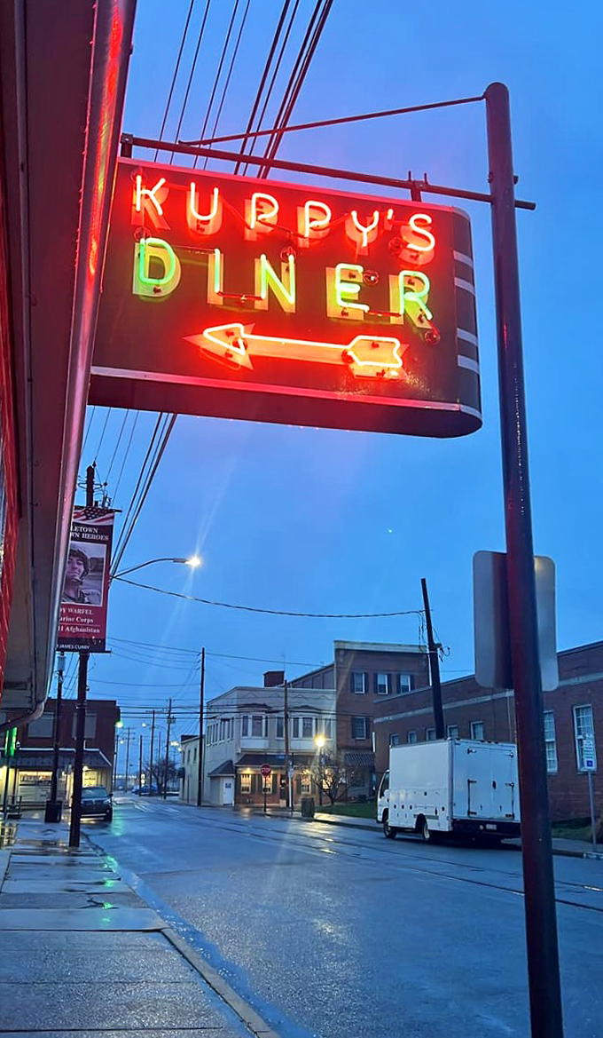 The neon sign glows like a beacon for hungry travelers. In the blue hour between day and night, Kuppy's promises comfort that transcends time.