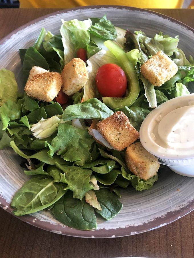 A house salad that actually deserves attention—crisp greens, cherry tomatoes, and homemade croutons that aren't just filling time before the main event.