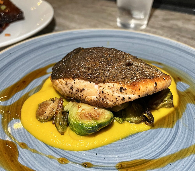 This perfectly seared salmon, floating on golden sauce with charred Brussels sprouts, makes "eating your vegetables" feel like a luxury, not a chore.